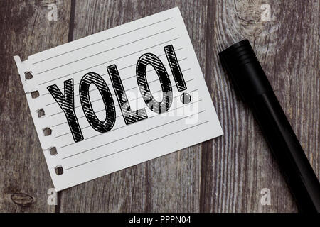 Hand writing the motto acronym YOLO - You Only Live Once with white ...