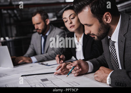 architects and engineers in suits working with blueprints together on ...