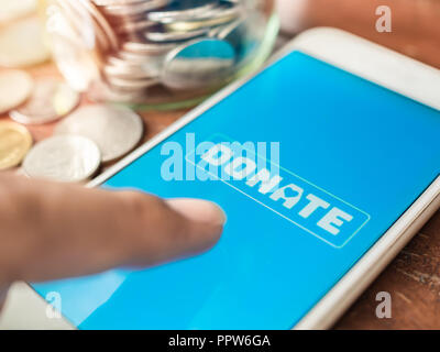 Close-up finger pressing donate button on smartphone screen. Donation ...