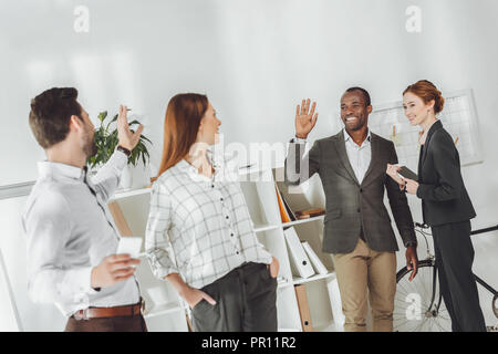 smiling multicultural businesspeople waving hands in office Stock Photo ...