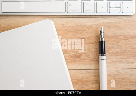 Office table with notepad, keyboard and fountain pen. View from above ...