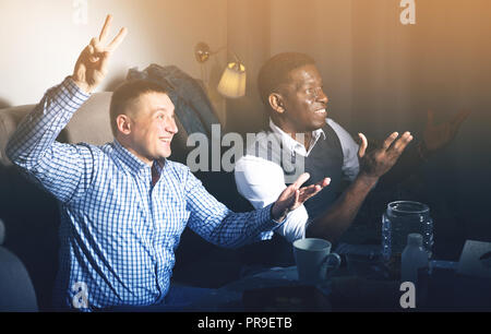 Two happy men emotionally watching tv at home Stock Photo - Alamy