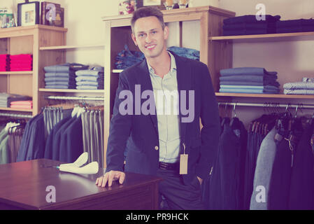 Customer examining suits in male cloths store Stock Photo - Alamy