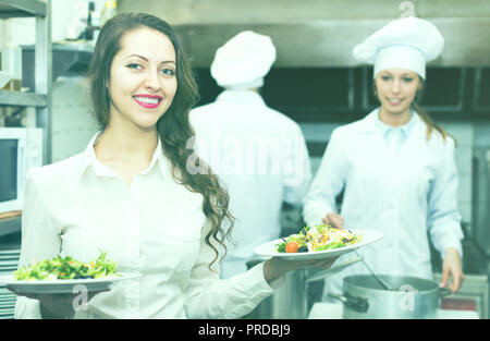 Team of positive chefs and young waiter in the restaurant kitchen Stock ...