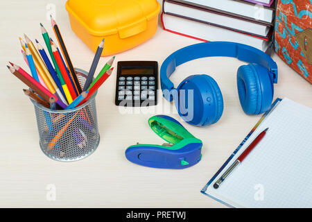 Yellow backpack with school stationery and headphones on bench in park ...