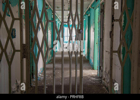 Steel gate across the corridor of prison cell doors inside an abandoned ...