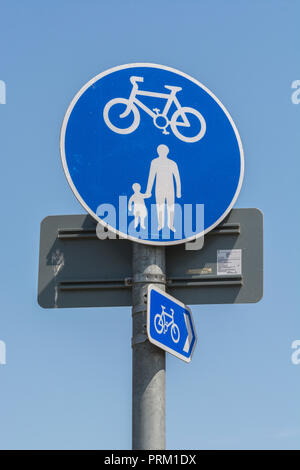 Cycle route sign with pedestrian figures set against blue summer sky in ...