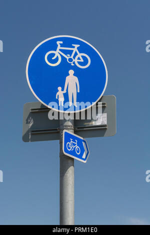 Cycle route sign with pedestrian figures set against blue summer sky in ...
