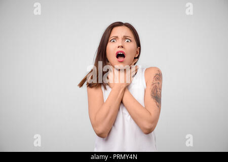 Brunette female holds head with panic stricken terror shocked ...