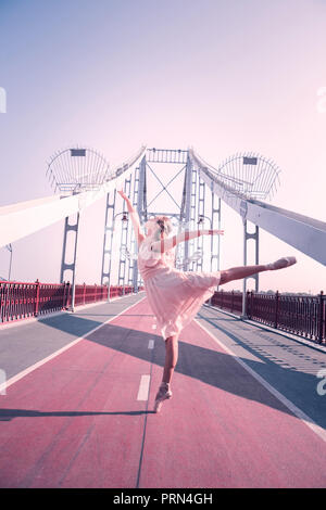 Flexible, tender, young woman, professional ballerina dancing over pastel background with ...