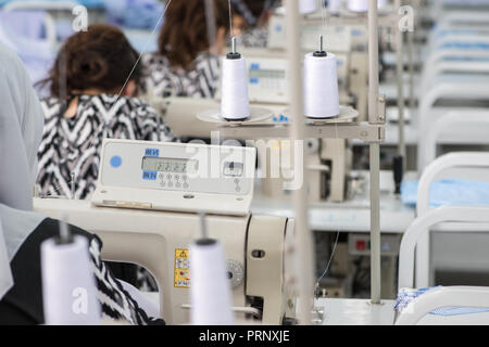 Garment workers at work on sewing machines inside a garment factory in ...