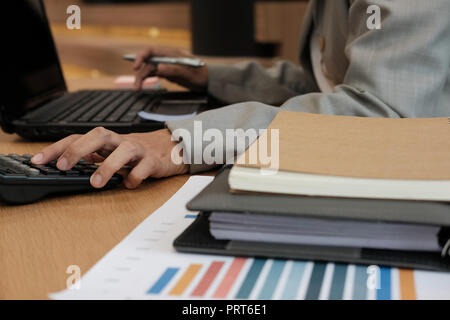 financial adviser working with calculator & computer at office ...