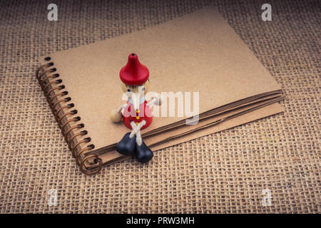 Pinocchio sitting on notebook on a canvas background Stock Photo - Alamy