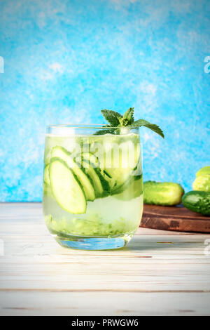 Fresh cucumber slices and mint leaves on a blue background, overhead ...