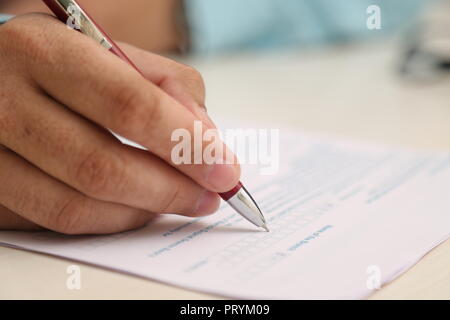 Man is filling form with pen. Picture of calculator, mouse and glasses ...