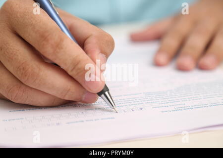 Man is filling form with pen. Picture of flower pot, computer, keyboard ...