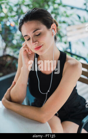 young, pretty businesswoman listening music in headphones and dancing ...