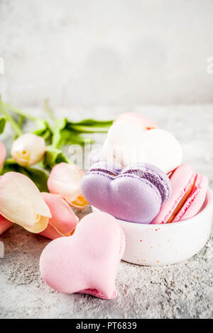 Pink heart homemade macaron cookies on parchment paper on a baking ...