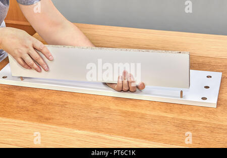 A furniture assembler connects parts of a wooden table, cam bolt ...