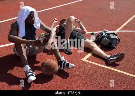 Exhausted basketball players taking a break on basketball court Stock ...