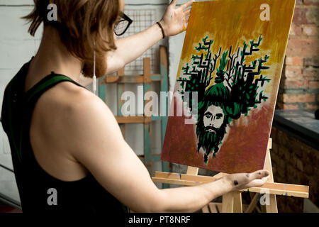 Portrait of contemporary male artist painting pictures standing by ...