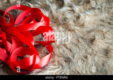 An artful swirl of shiny red satin ribbon set on the left side of a ...