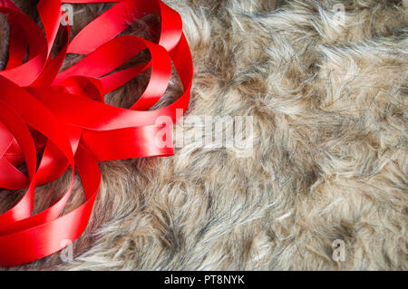 An artful swirl of shiny red satin ribbon set on the left side of a ...