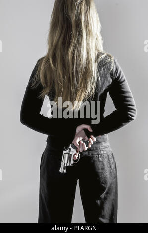 Woman holding a gun behind her back Stock Photo: 22337696 - Alamy