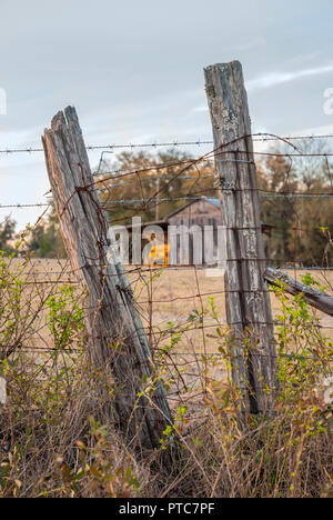 Rustic fence on a farm with barbed wire strands on metal droppers ...