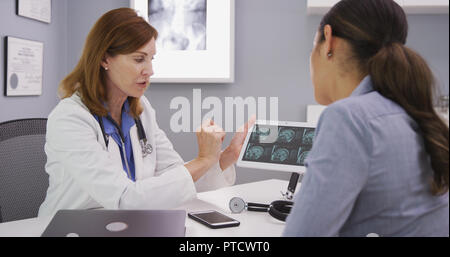 Young latina patient reviewing ct scan of cranium with middle aged ...