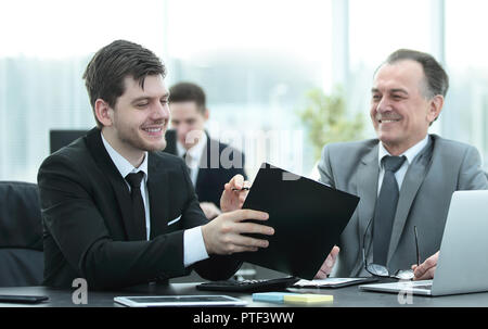 adult businessman discussing financial documents with a young colleague ...