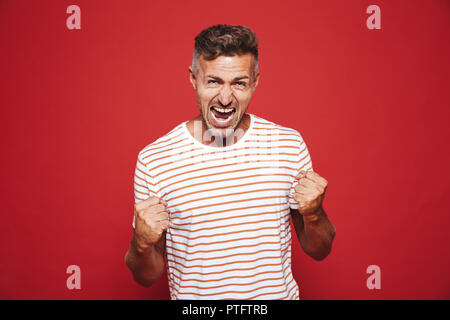 Furious adult man in striped t-shirt screaming and touching face ...