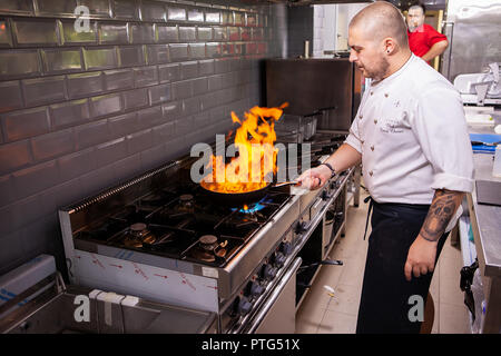 Male cook making flambe seafood at stove in restaurant kitchen.Tasty ...
