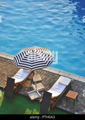 Swimming pool with chaise lounge and sunshade at tropical resort Summer ...