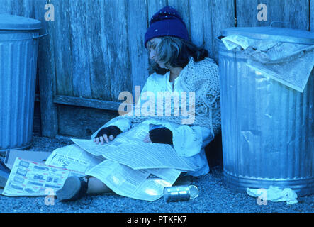 Homeless woman sleeping with garbage cans under newspaper blanket, USA ...