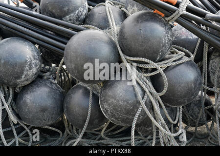 Black spherical plastic floats of fishing nets out of the water in port ...