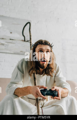 Emotional man with video game controller on grey background Stock Photo ...