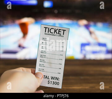 Bookmaker ticket on the background of a TV on which show skating sports ...