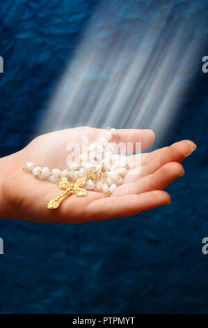 Christian cross with rosary beads into the light ray. Religion and ...