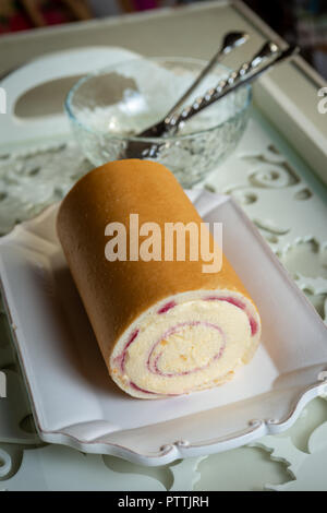 Arctic roll cake on a plate on a tray next to a spoon and a fork on a ...