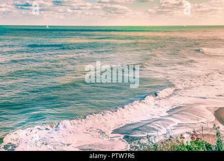 The waves of the turquoise sea break on the coastal boulders and a ...