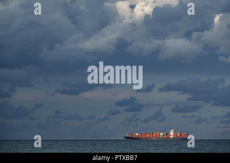 Cargo ship on top of the horizon at sunset Stock Photo - Alamy