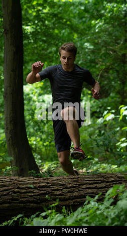 the guy jumps over a large log while participating in an ocr race Stock ...