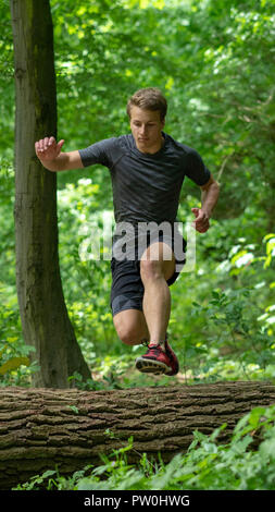 the guy jumps over a large log while participating in an ocr race Stock ...