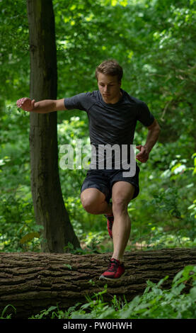 the guy jumps over a large log while participating in an ocr race Stock ...