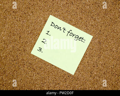 Don't forget reminder message written on yellow post-it note close up ...