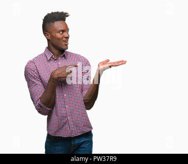 Young amazed African American pointing his finger at white background ...