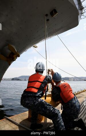 US Navy Four line handlers heave in one of the mooring lines Stock ...
