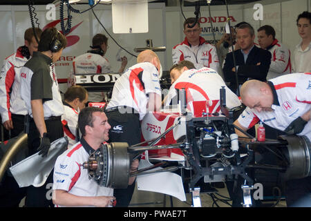 F1 mechanics at work on a Honda F1 race car in the pit lane workshop ...