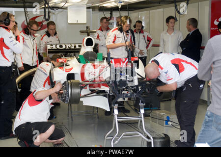 F1 mechanics at work on a Honda F1 race car in the pit lane workshop ...